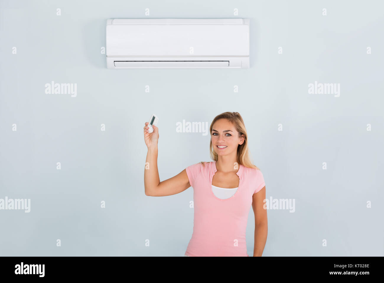 Woman Operating Air Conditioner With Remote Stock Photo - Alamy