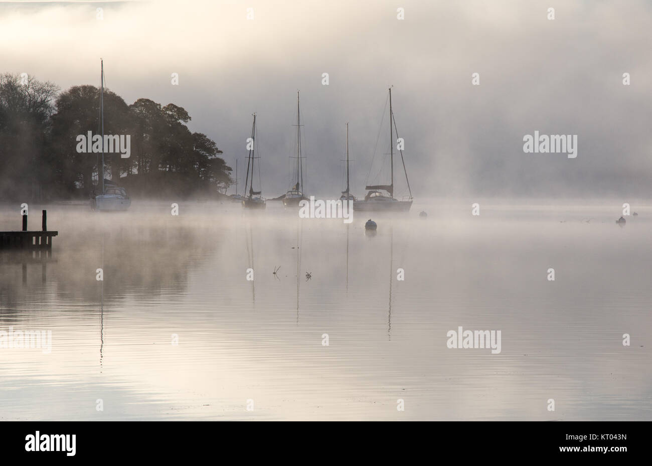 Mist rises around boats moored on Windermere lake at Ambleside in ...