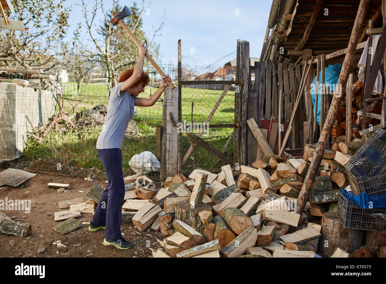 Woman with an ax splitting beech logs for firewood Stock Photo - Alamy