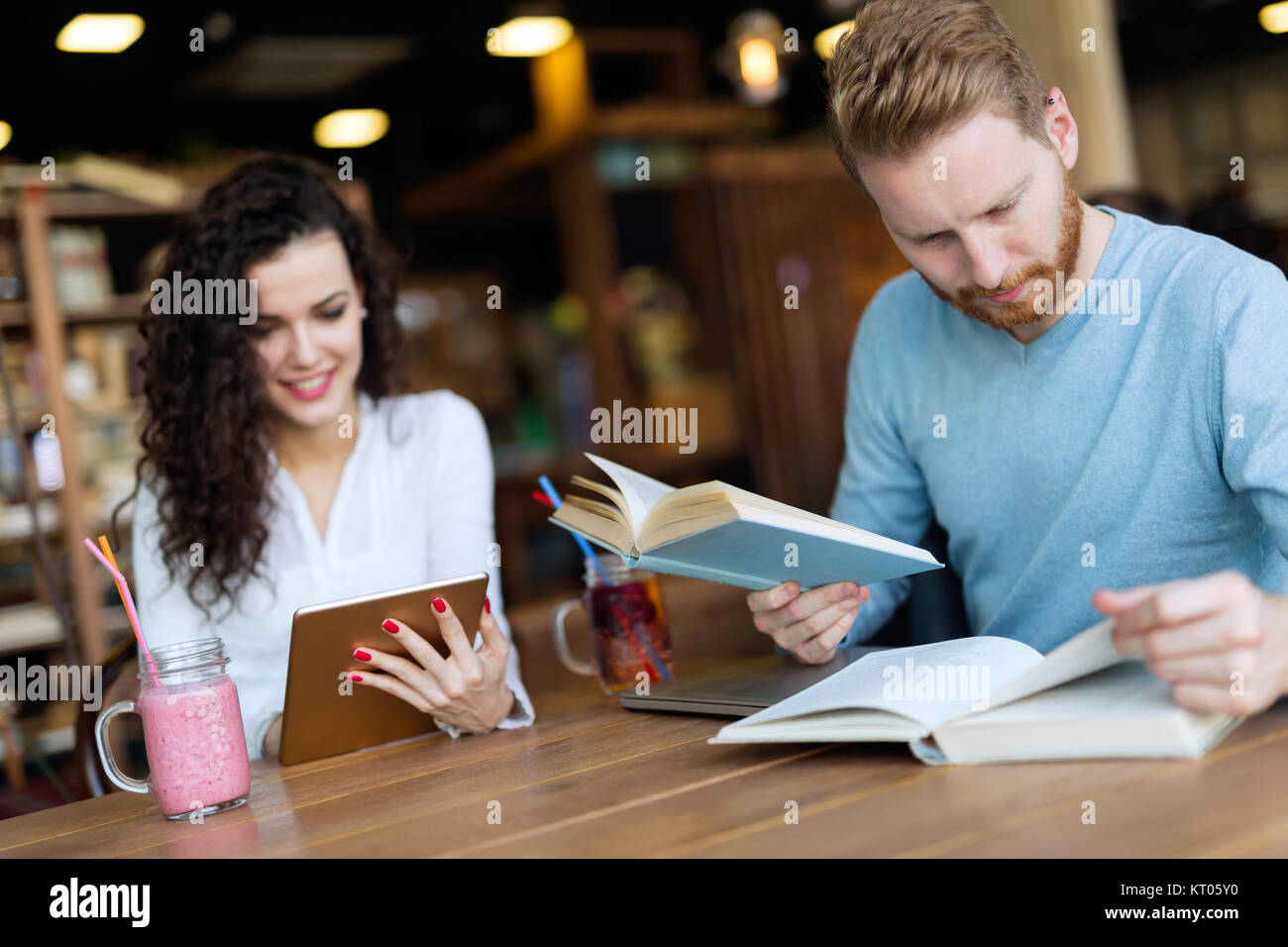 Young students spending time in coffee shop reading books Stock Photo ...