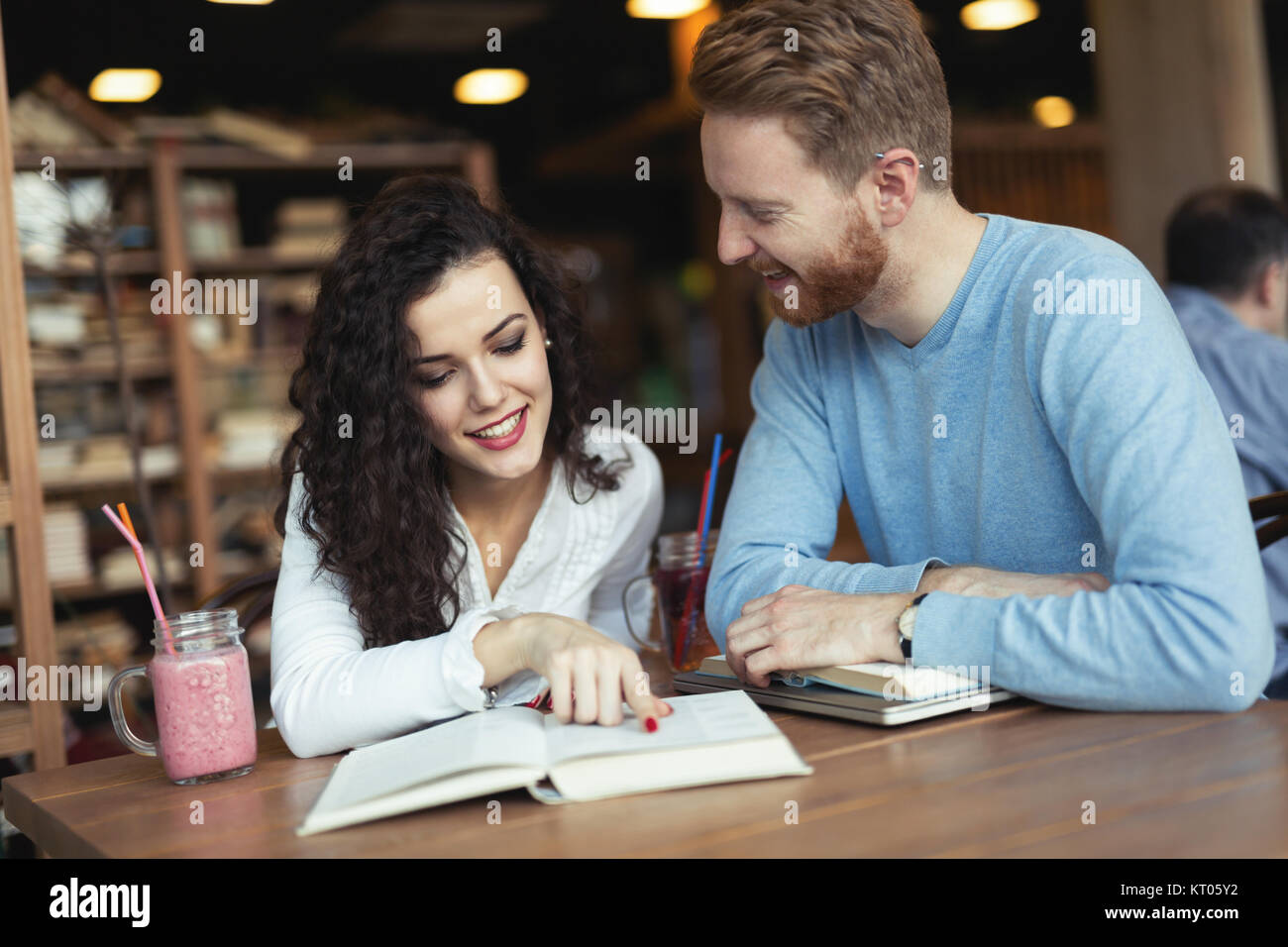 Young students spending time in coffee shop reading books Stock Photo ...