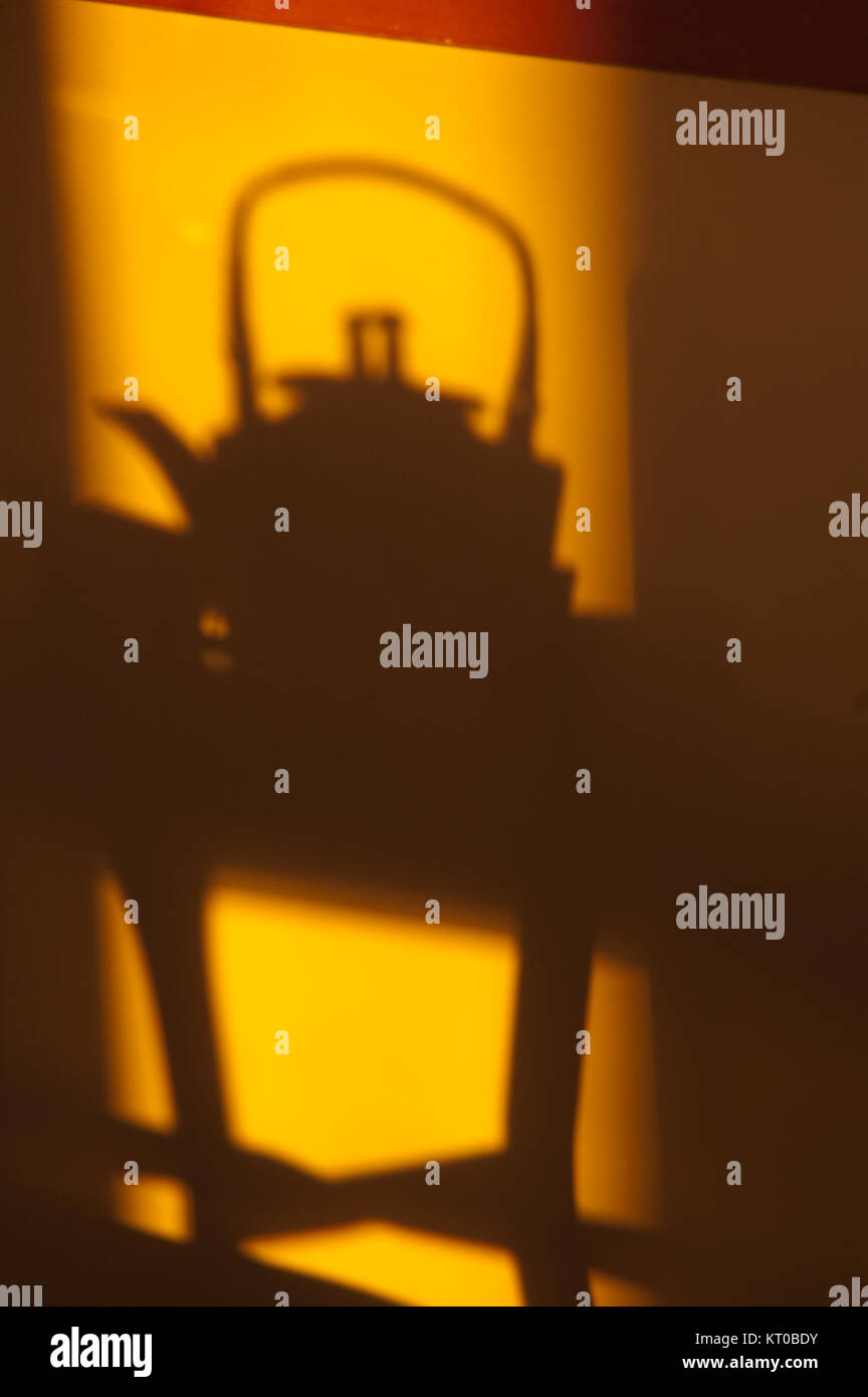 Silhouette tea pot shadow reflected in an apartment wall at sunset ...