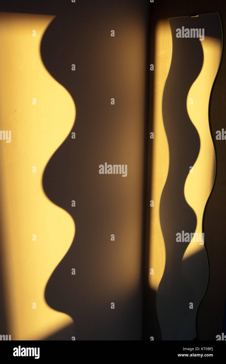 Silhouette mirror shadow reflected in an apartment wall at sunset. Late ...