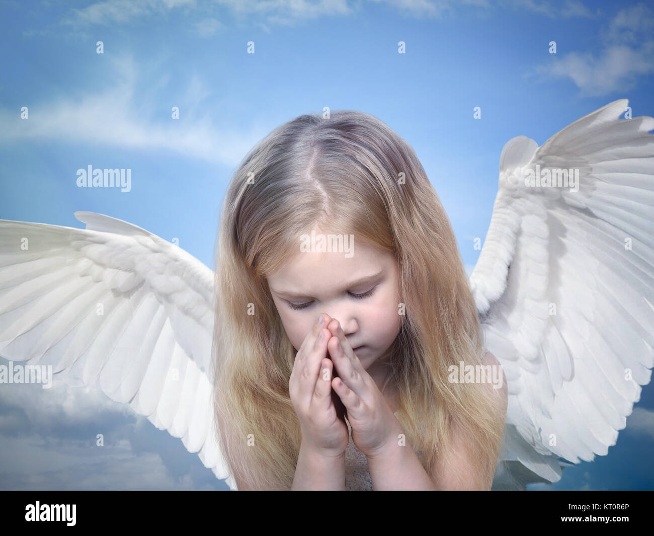 Little girl angel with wings. A child prays. The background of blue sky ...