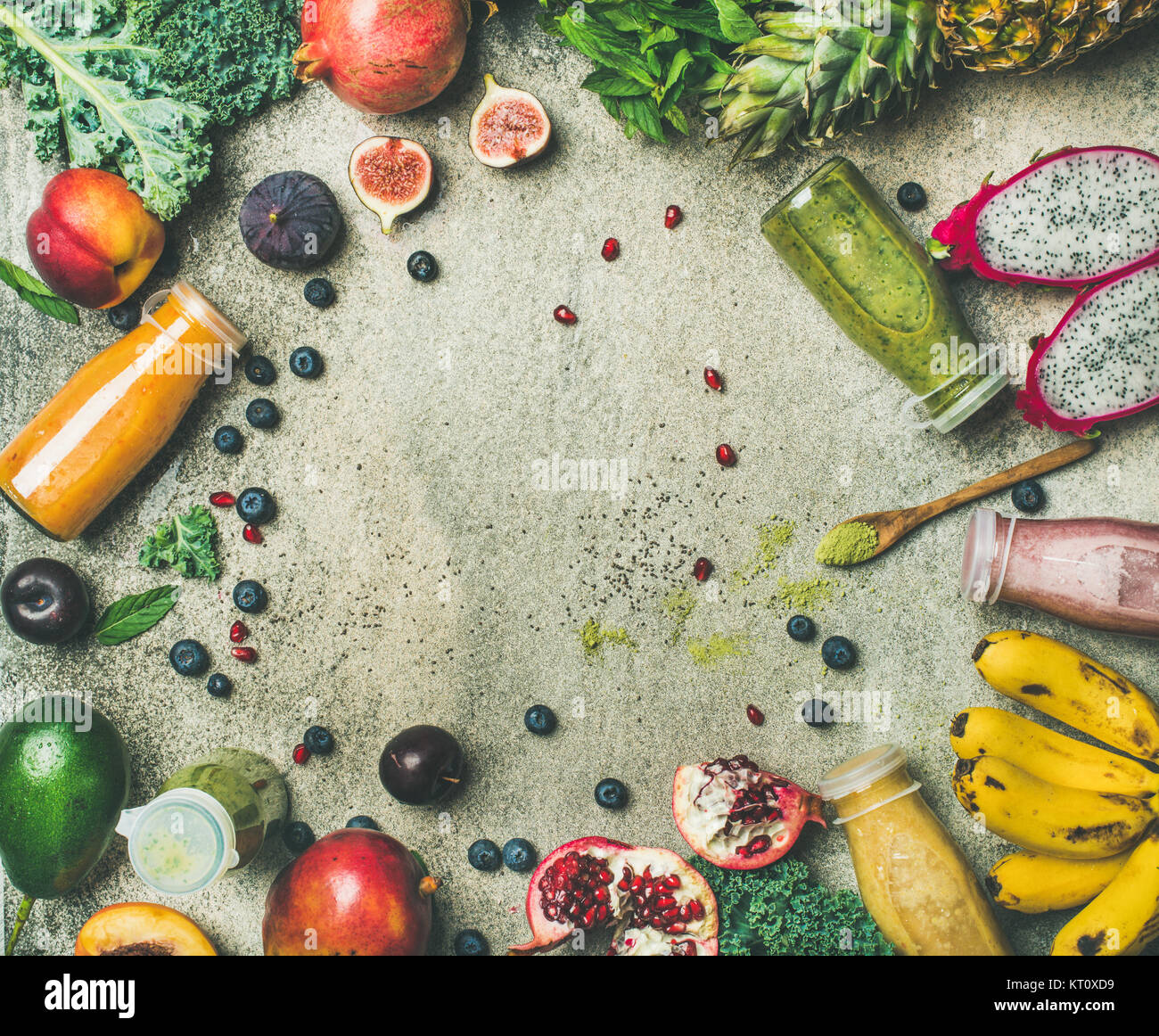 Colorful smoothies in bottles with fresh tropical fruit and greens on ...