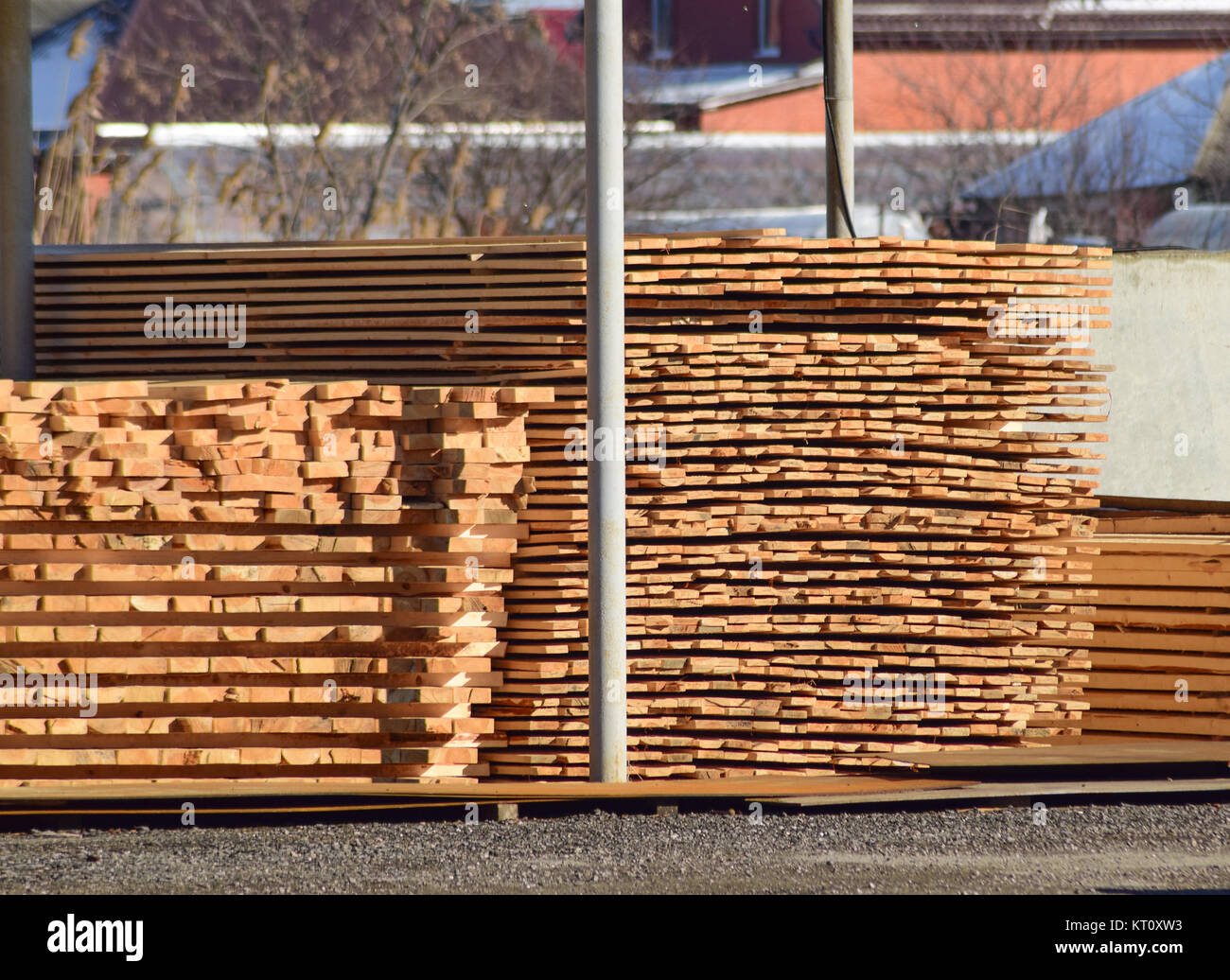 Warehouse of building materials, wood planks stacked under a canopy ...
