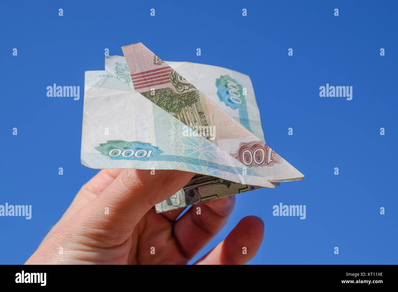 Denominations of Russian money, folded in the airplane against the blue ...