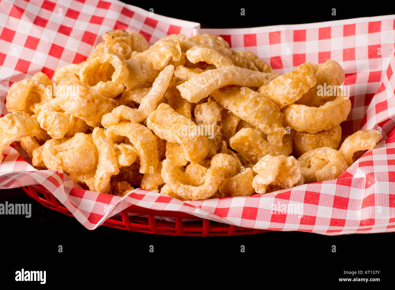 Delicious crispy pork rinds. A crisp salty snack on black glossy ...