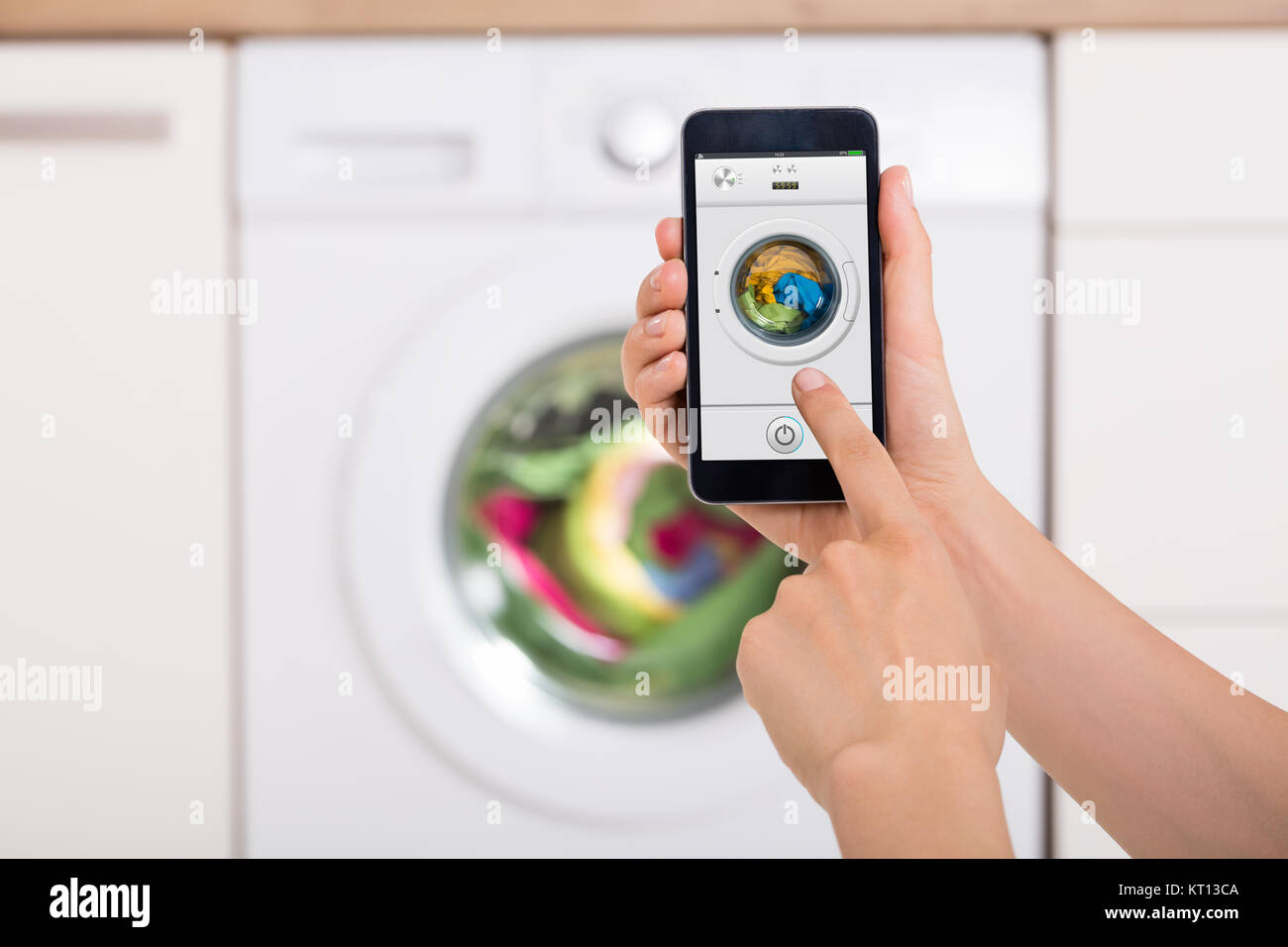 Woman Using Mobile Phone To Operate Washing Machine Stock Photo - Alamy