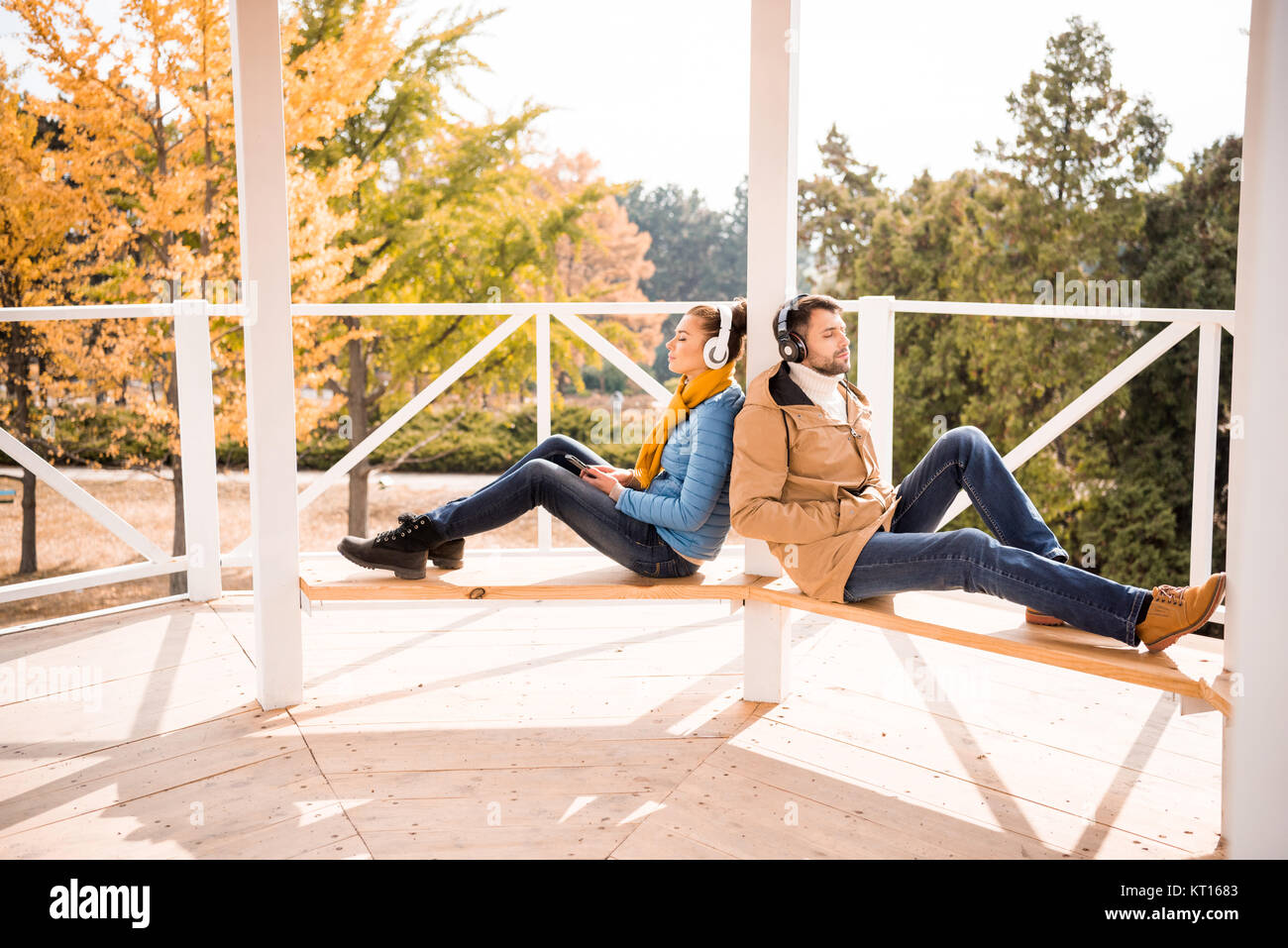 Young couple sitting on bench in headphones Stock Photo - Alamy