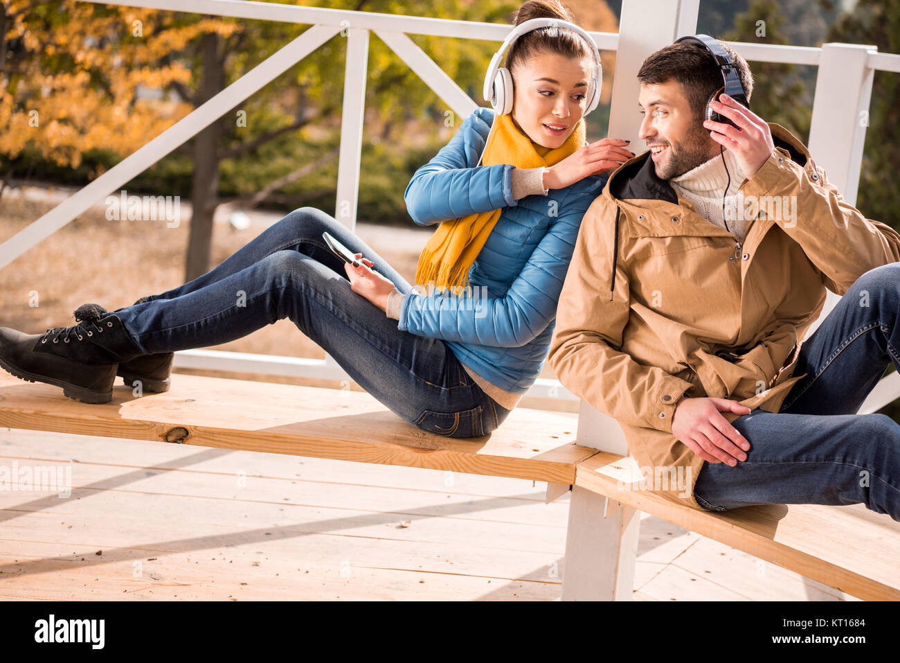 Young couple sitting on bench in headphones Stock Photo - Alamy
