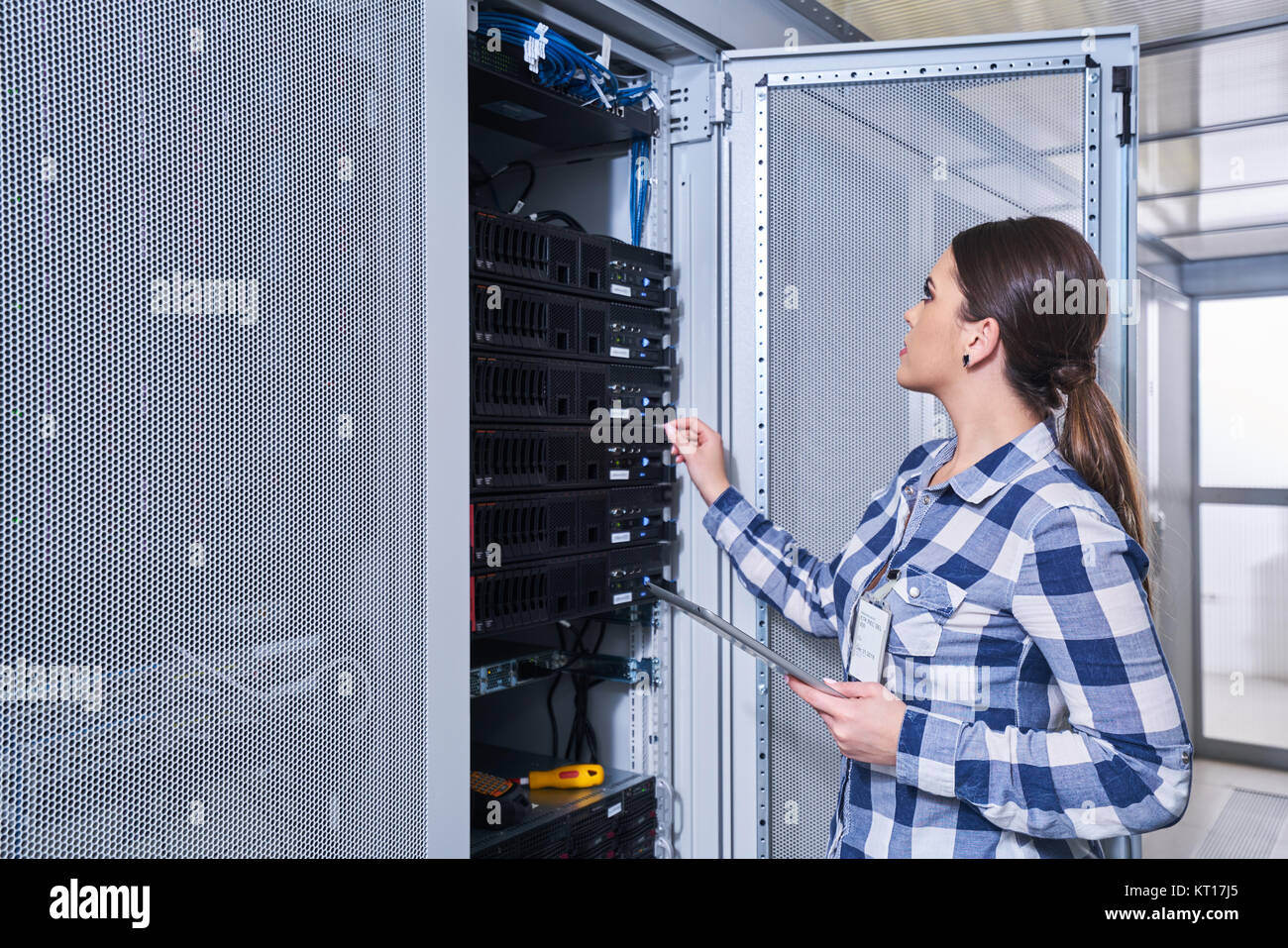 female technician working on server maintenance in white server room ...
