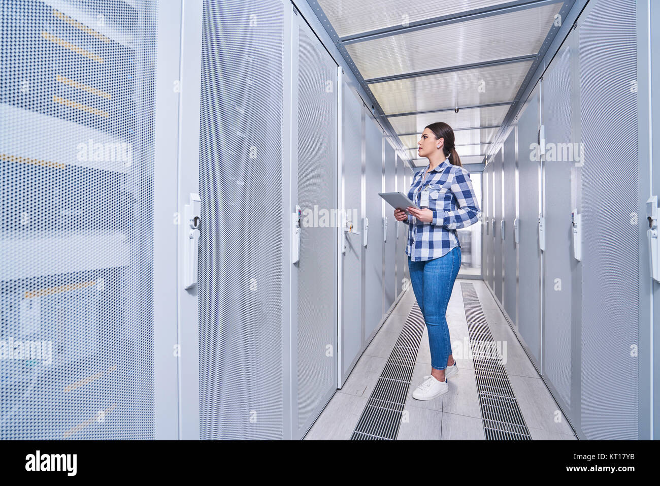 female technician working on server maintenance in white server room ...