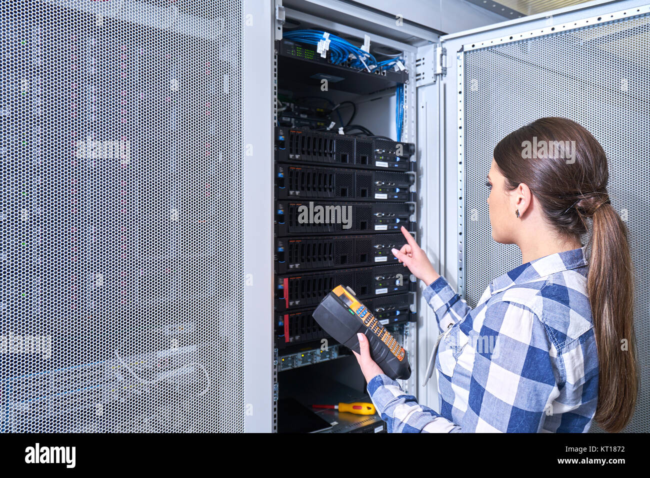 female technician working on server maintenance in white server room ...