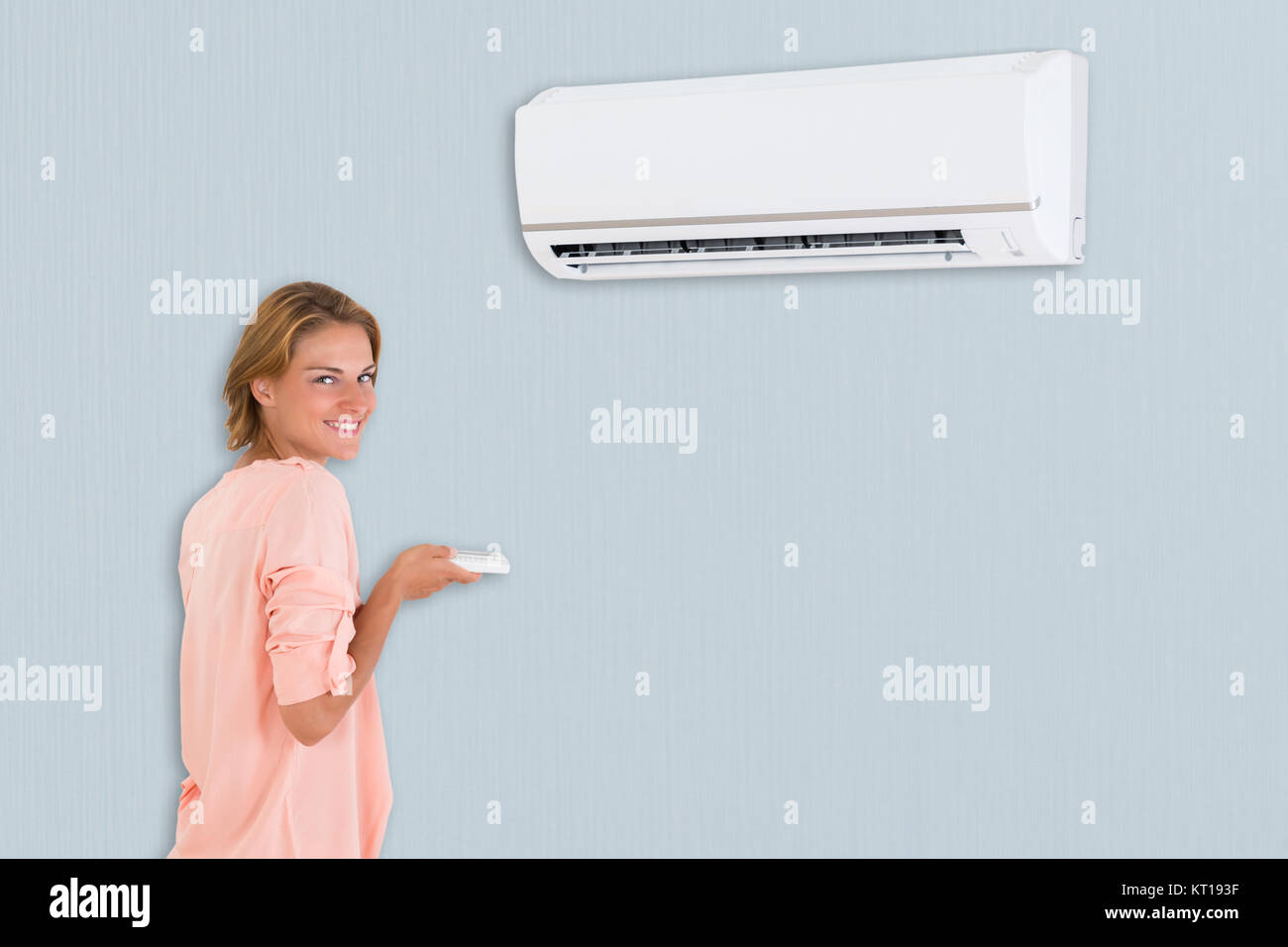 Woman Operating Air Conditioner Stock Photo - Alamy