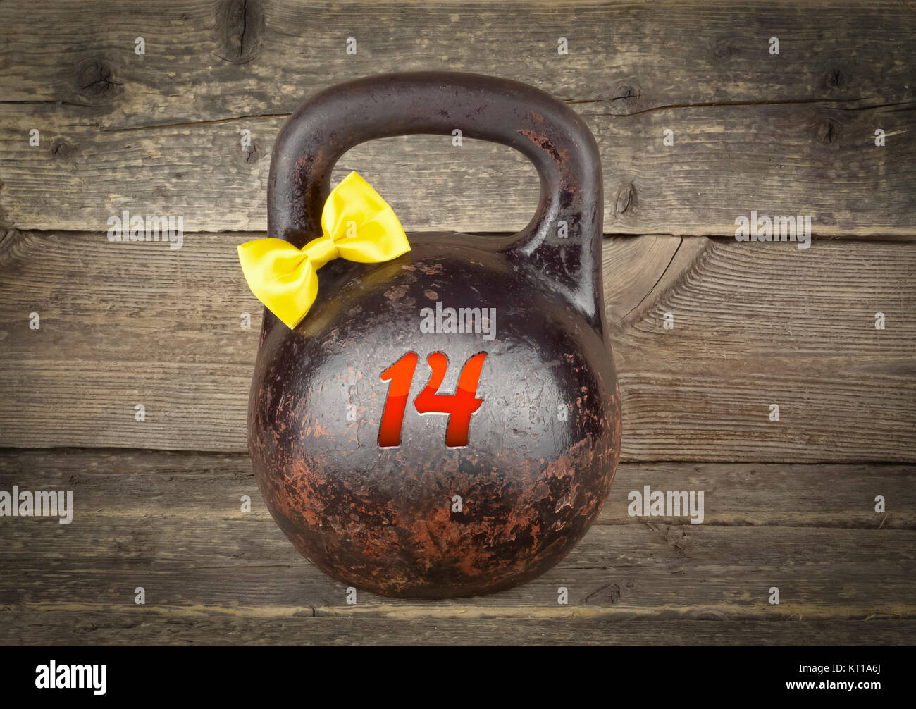 Yellow tied bow on Old rusty Kettlebell over wooden table with number ...