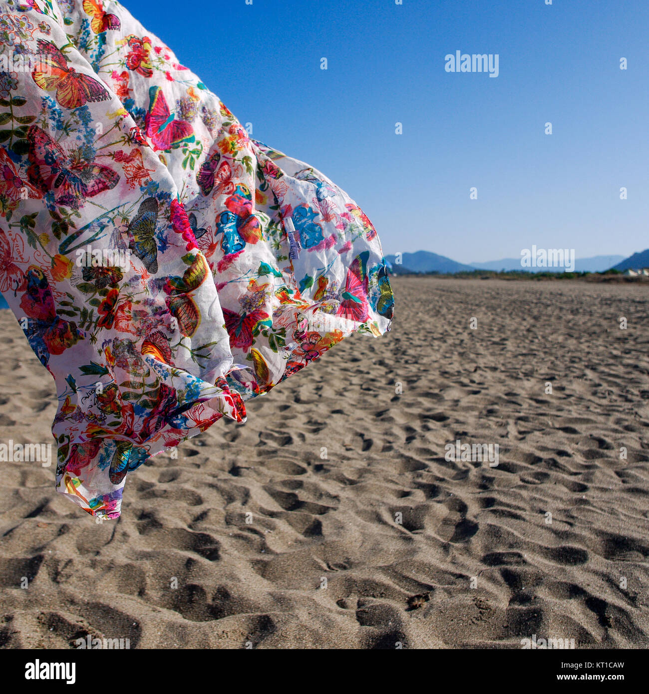 Colored piece of fabric flying in the wind on a white sand beach ...
