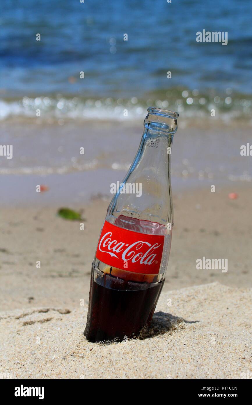 A coke buried in the sand in the beach Stock Photo - Alamy