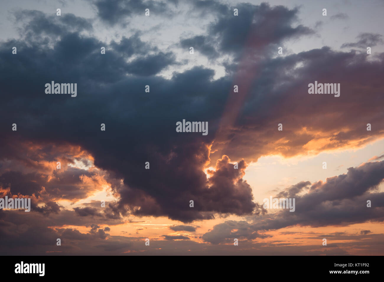 A colorful sunset sky with rays of sun. Dark grey clouds with bright ...