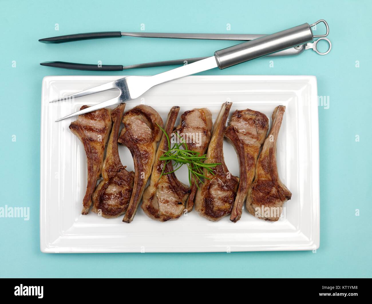 Cooked lamb chops on a plate isolated against a blue background Stock ...