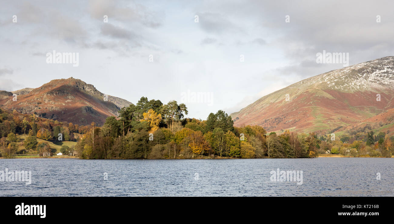 Trees display autumn colours beside snow-capped mountains on Grasmere ...