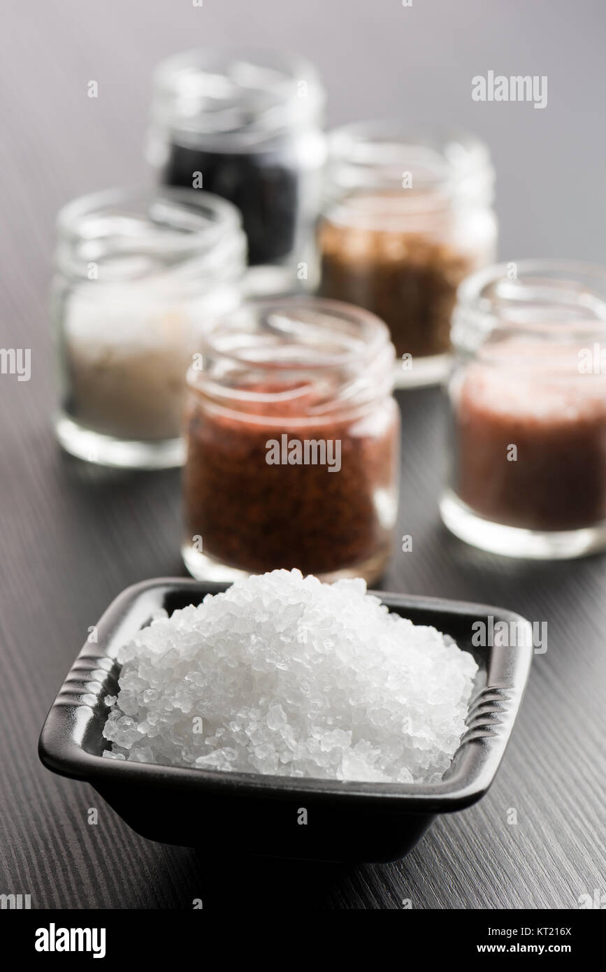 black bowl with coarse salt with variety of salt on black table Stock ...