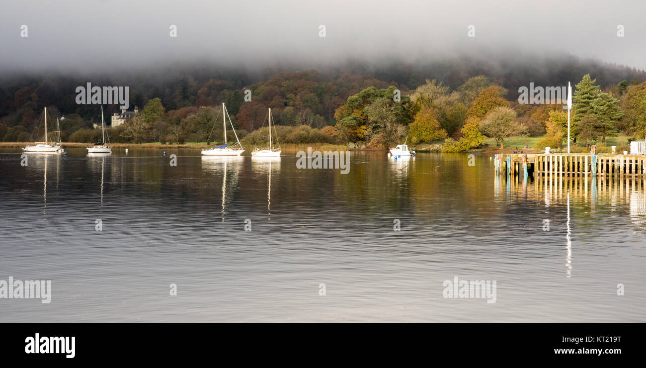 Mist rises from woodland in autumn colour at Ambleside on Windermere ...