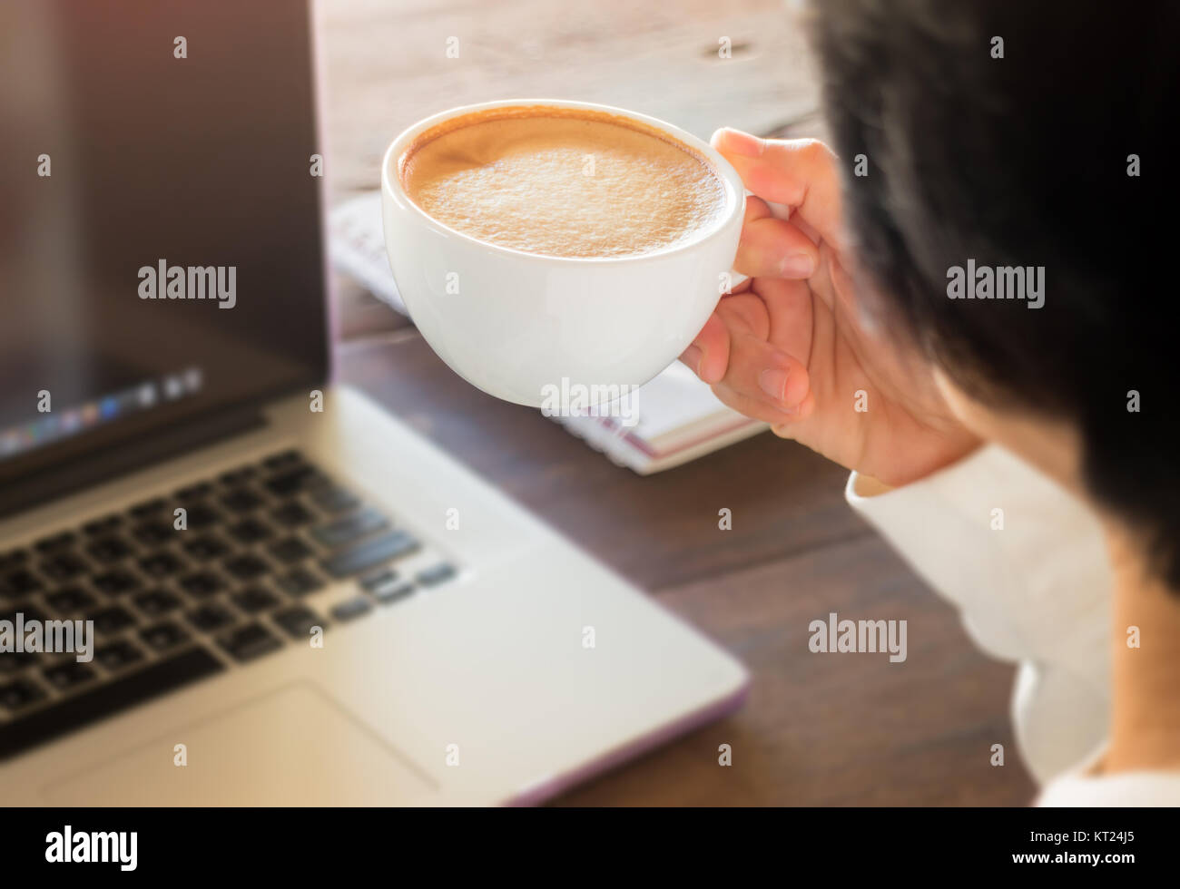Hand on cup of coffee at work table Stock Photo - Alamy