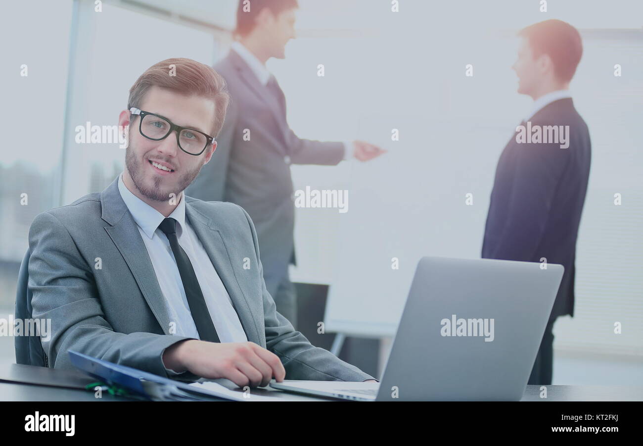 Portrait of a handsome young business man with people in background at ...