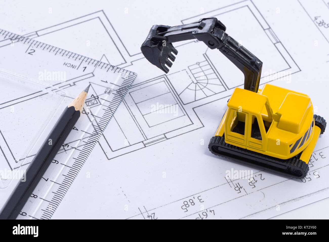 Desktop with blueprint yellow mini excavator, ruler and pencil ...