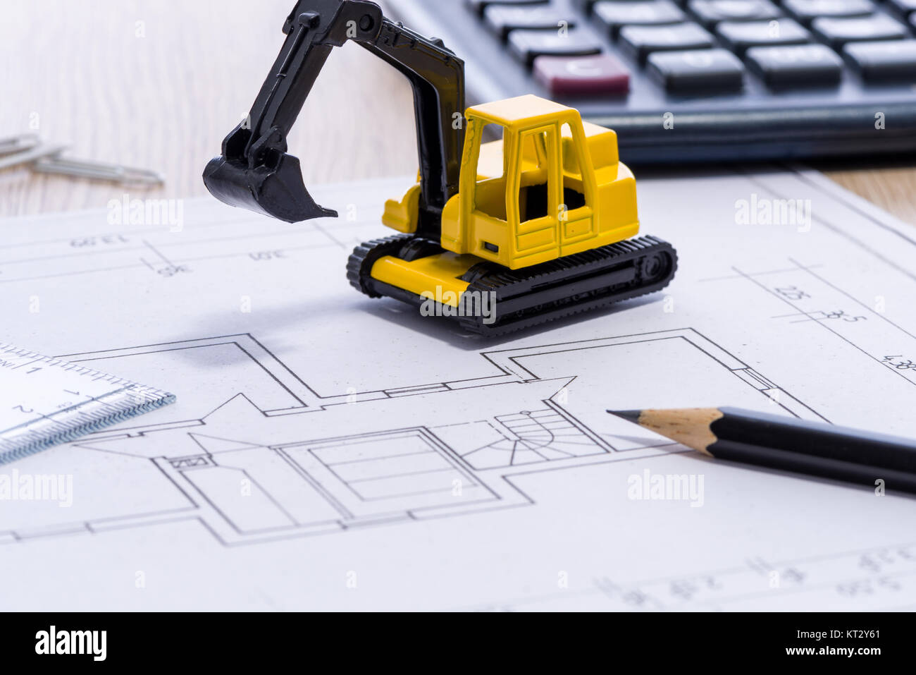Desktop with blueprint yellow mini excavator, ruler, pencil and ...