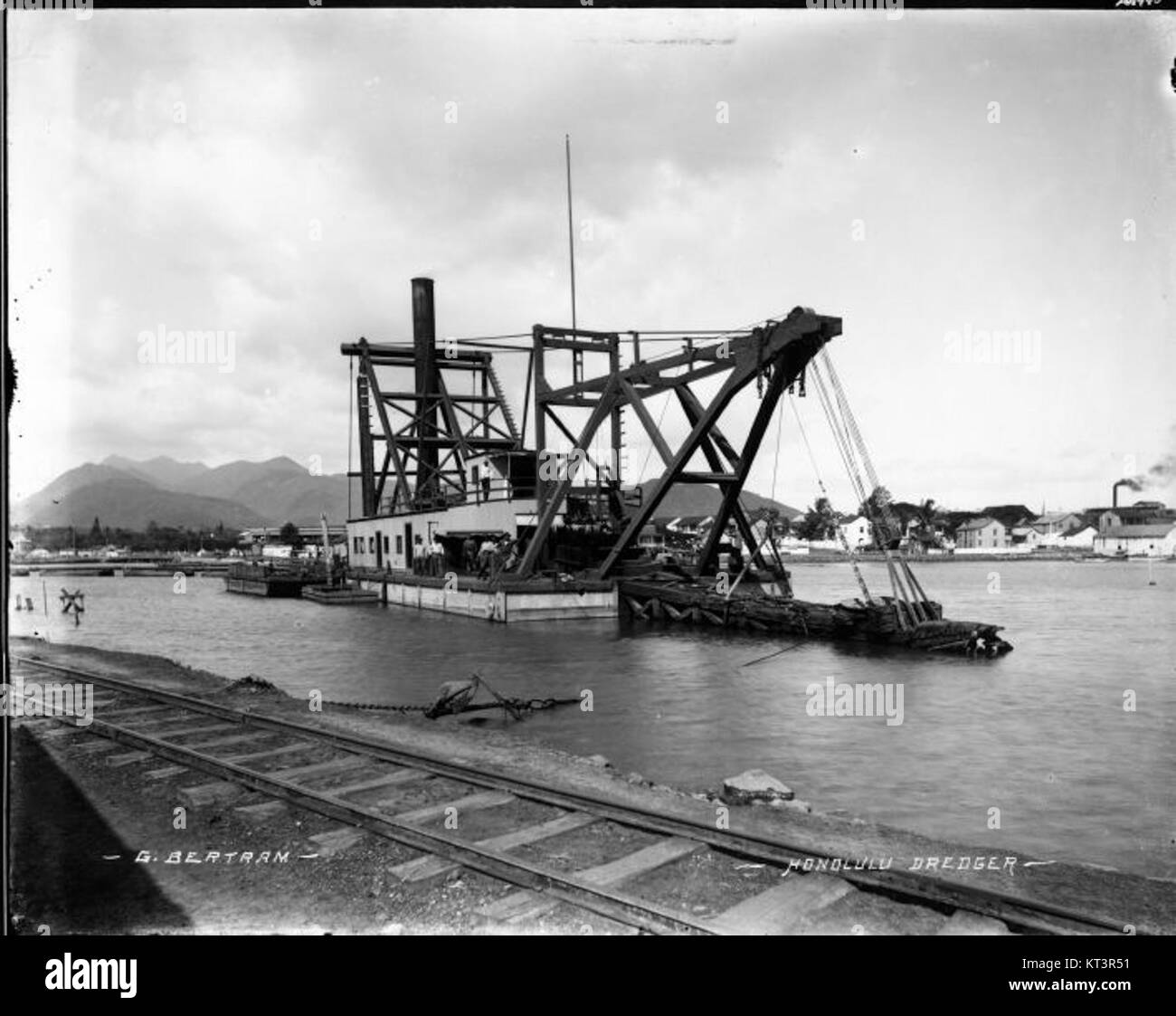 The photograph depicts the Honolulu dredger working in Honolulu Harbor ...