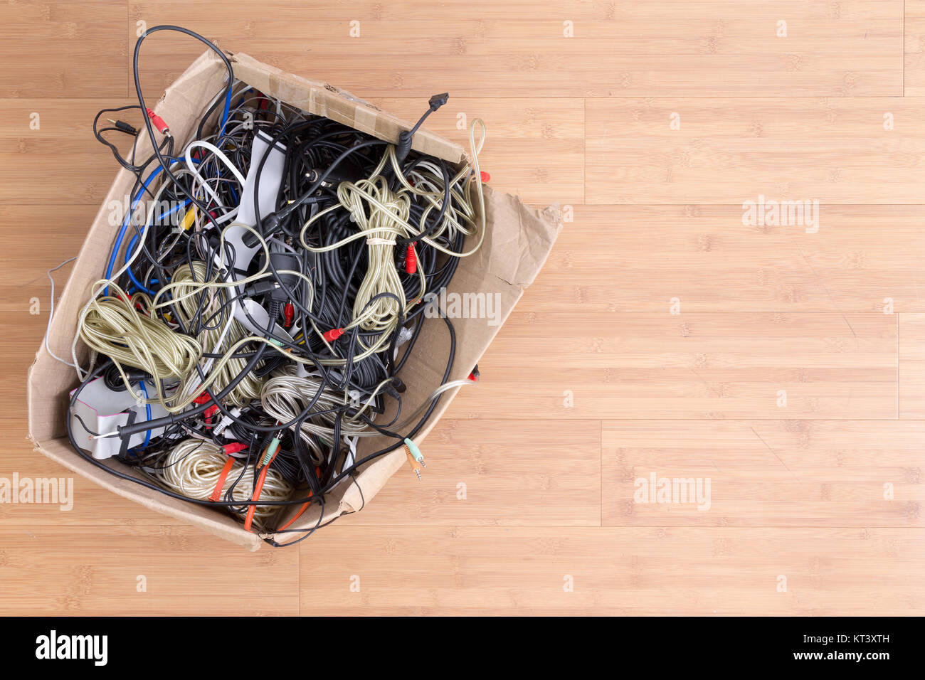 Old battered cardboard box with electrical cords and connectors for ...