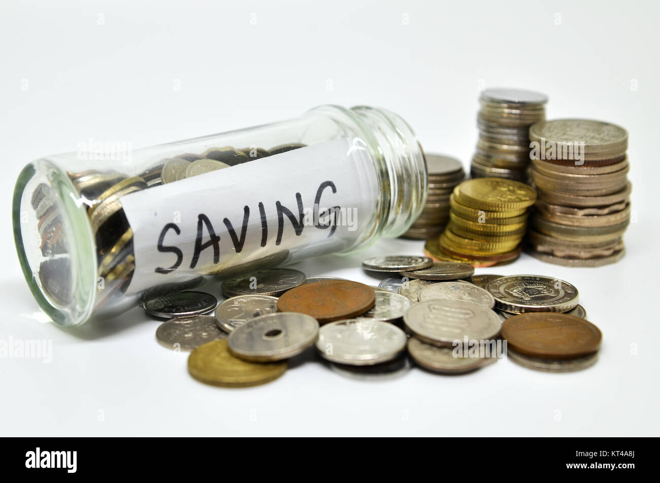 Saving lable in a glass jar with coins spilling out Stock Photo - Alamy