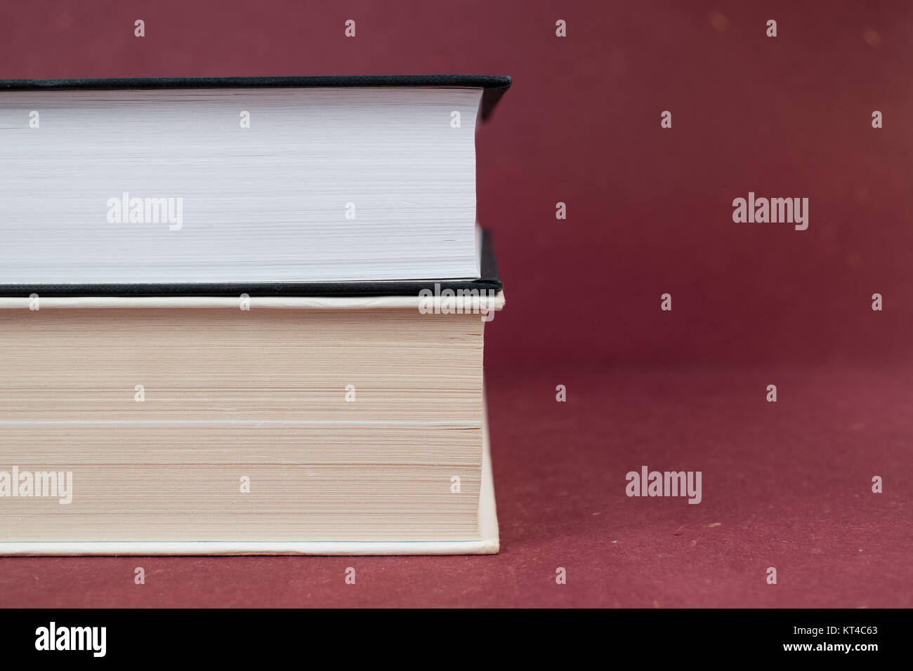 Two hardcover books on each other on a red background. White and black ...