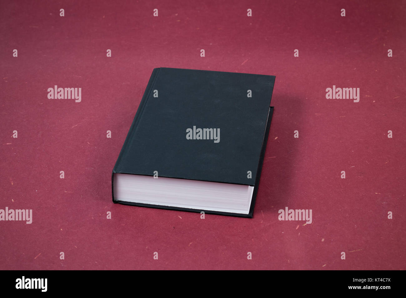 Big black closed hardcover book on red background Stock Photo - Alamy