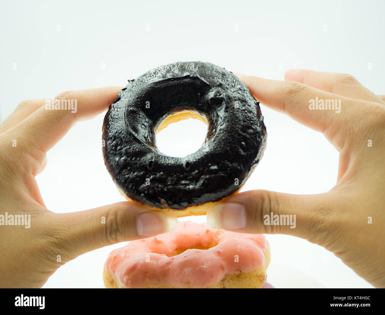 Woman's hand holding donut on white background Stock Photo - Alamy