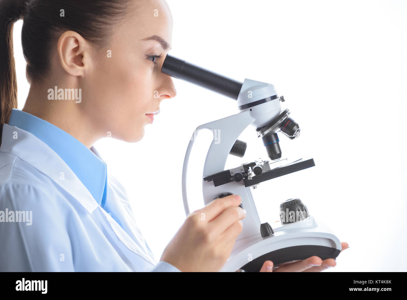 side view of concentrated woman scientist looking through microscope on ...