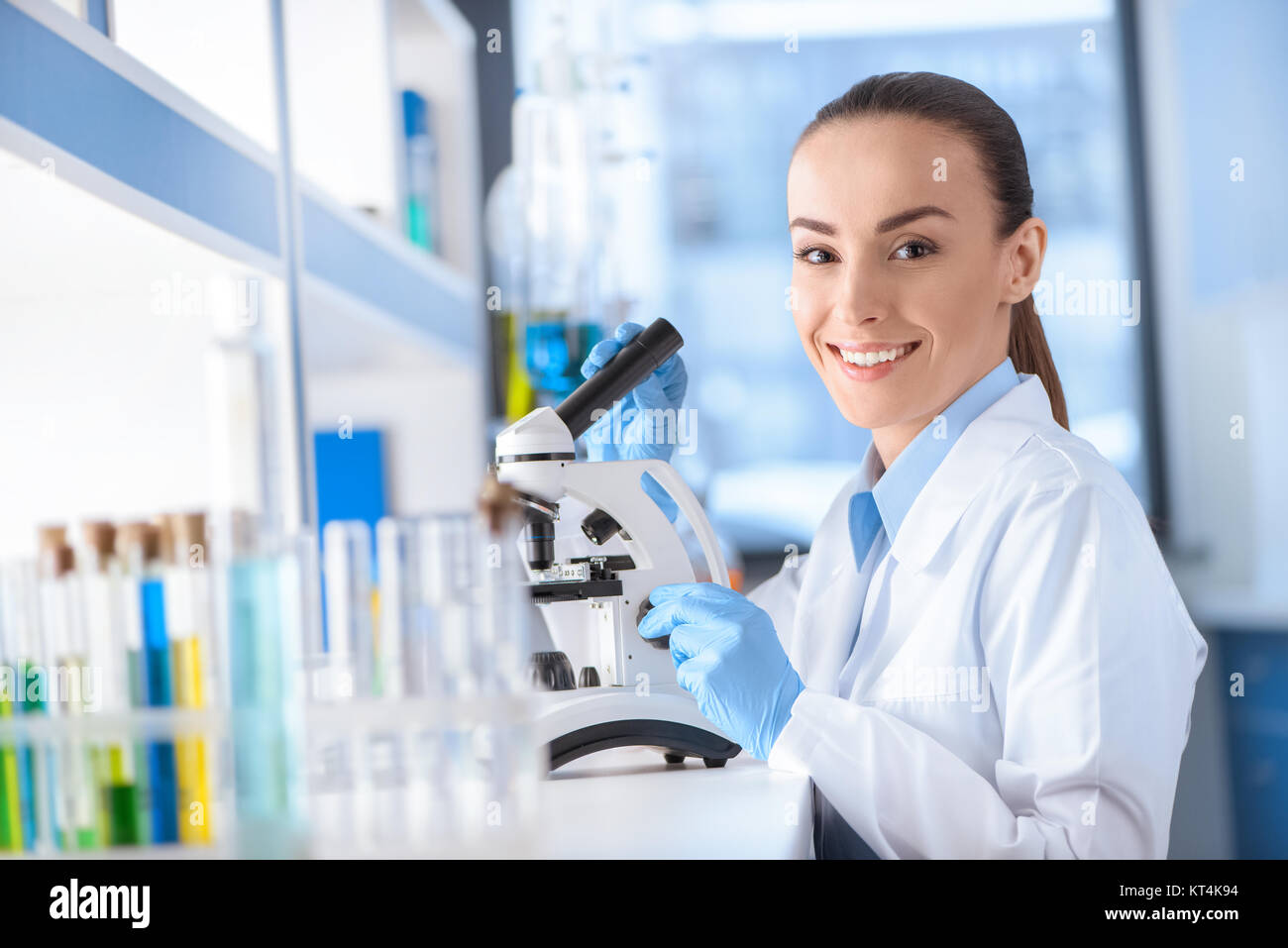 portrait of smiling scientist working with microscope and looking to ...