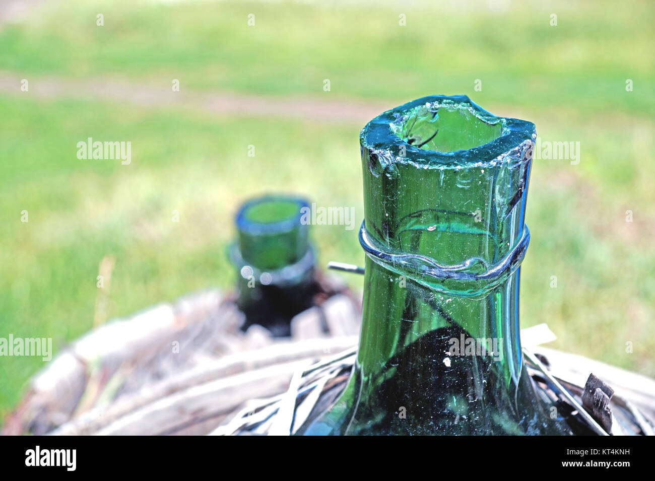 Old demijohn glass wrapped in wicker abandoned Stock Photo - Alamy