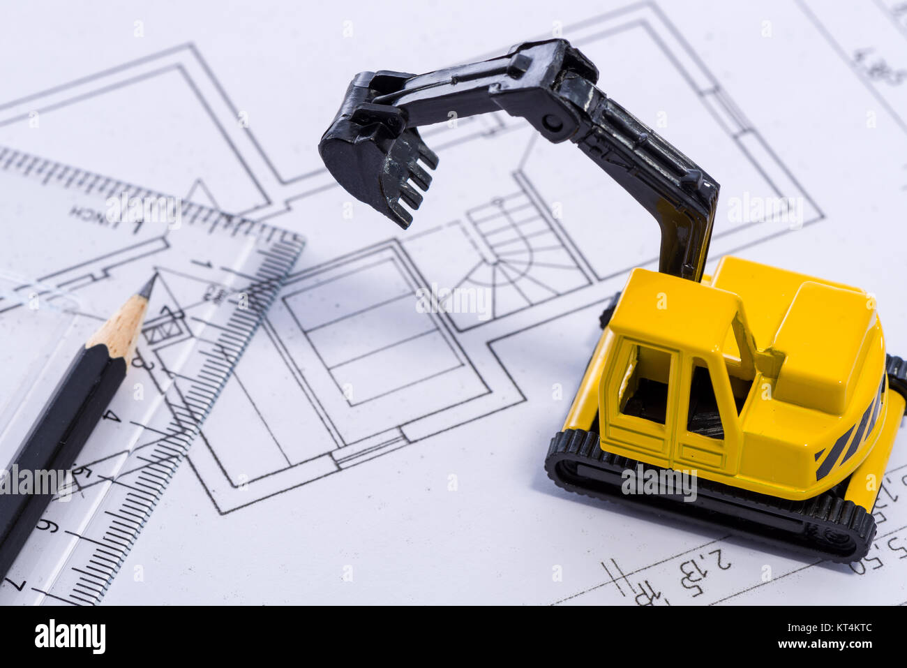 Desktop with blueprint yellow mini excavator, ruler and pencil ...