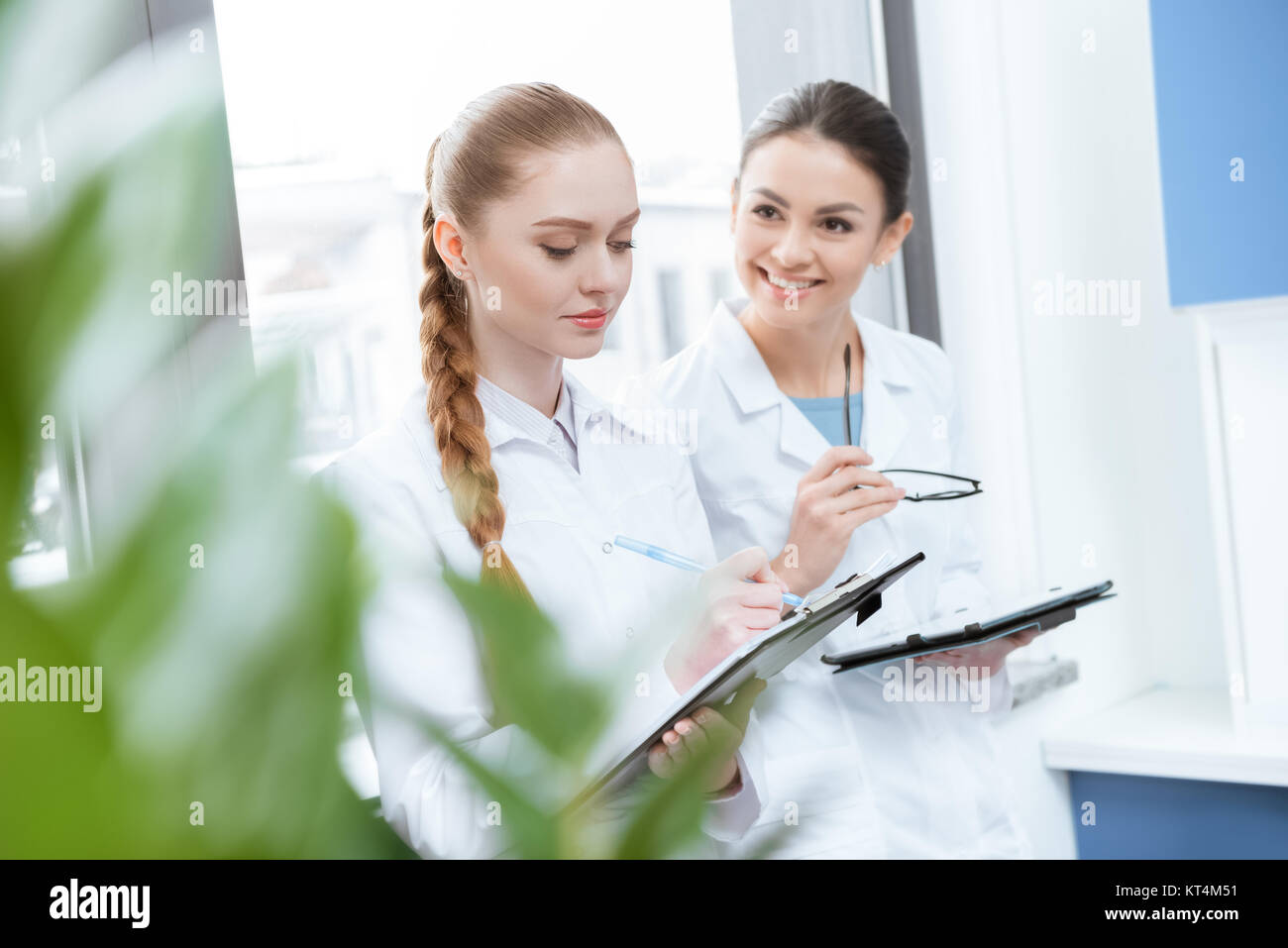 Young women scientists in white coats holding clipboard and digital ...