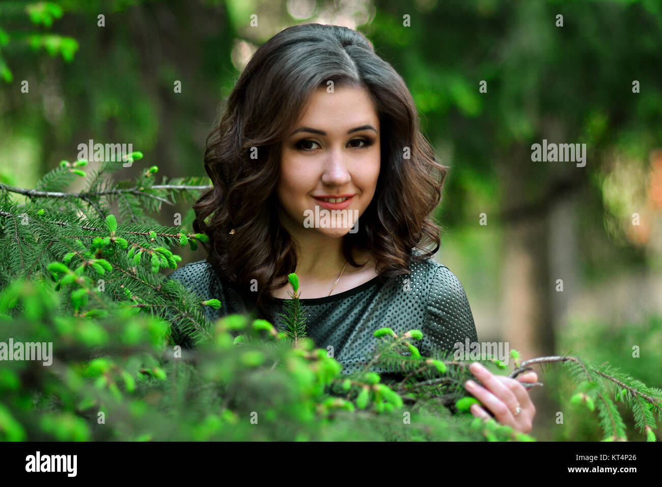 Smiling woman.Attractive girl in green dress stand in spring green park ...