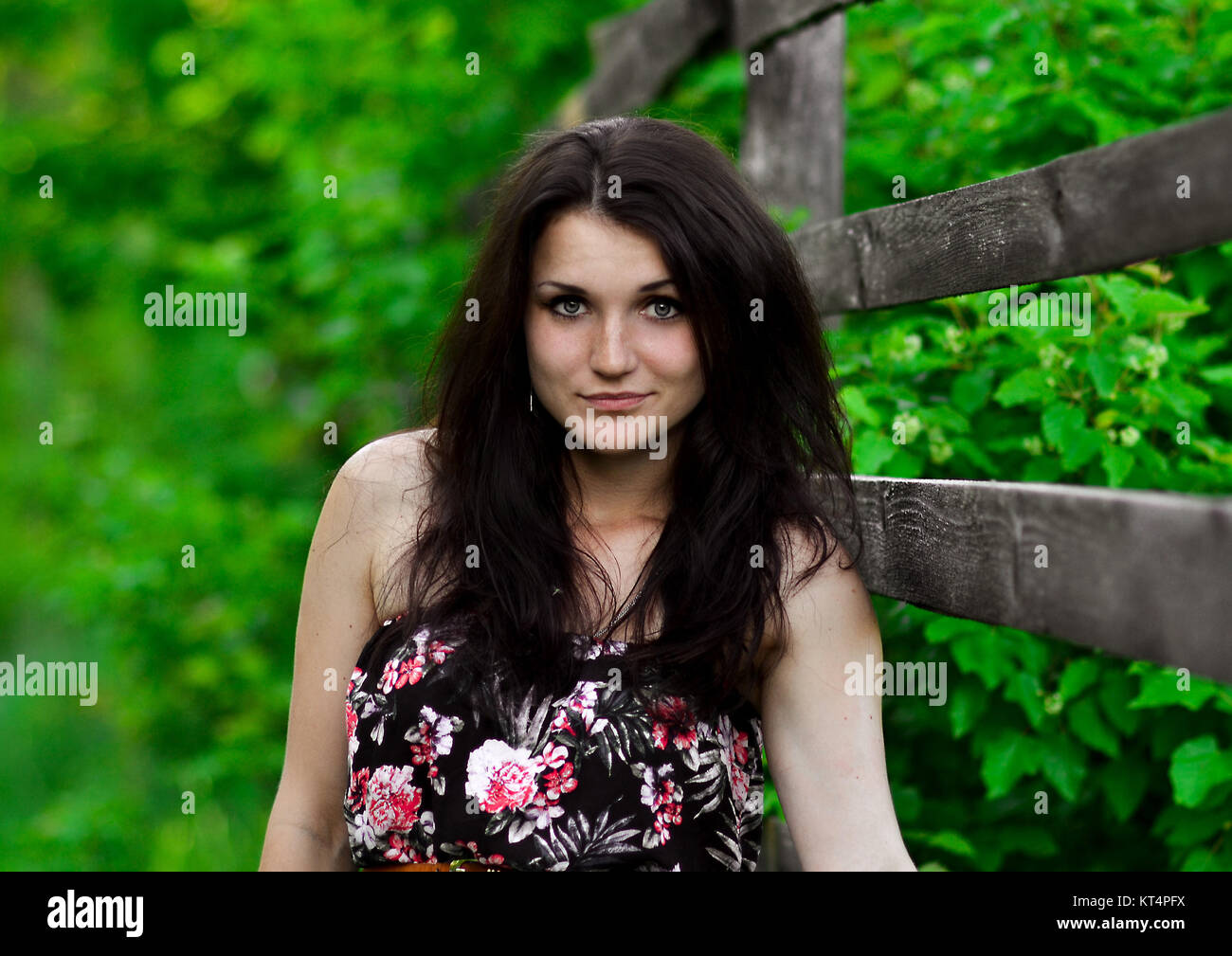 Nice Brunette Girl Stand Near The Wooden Fence And Green Trees In Summer Forest Beautiful