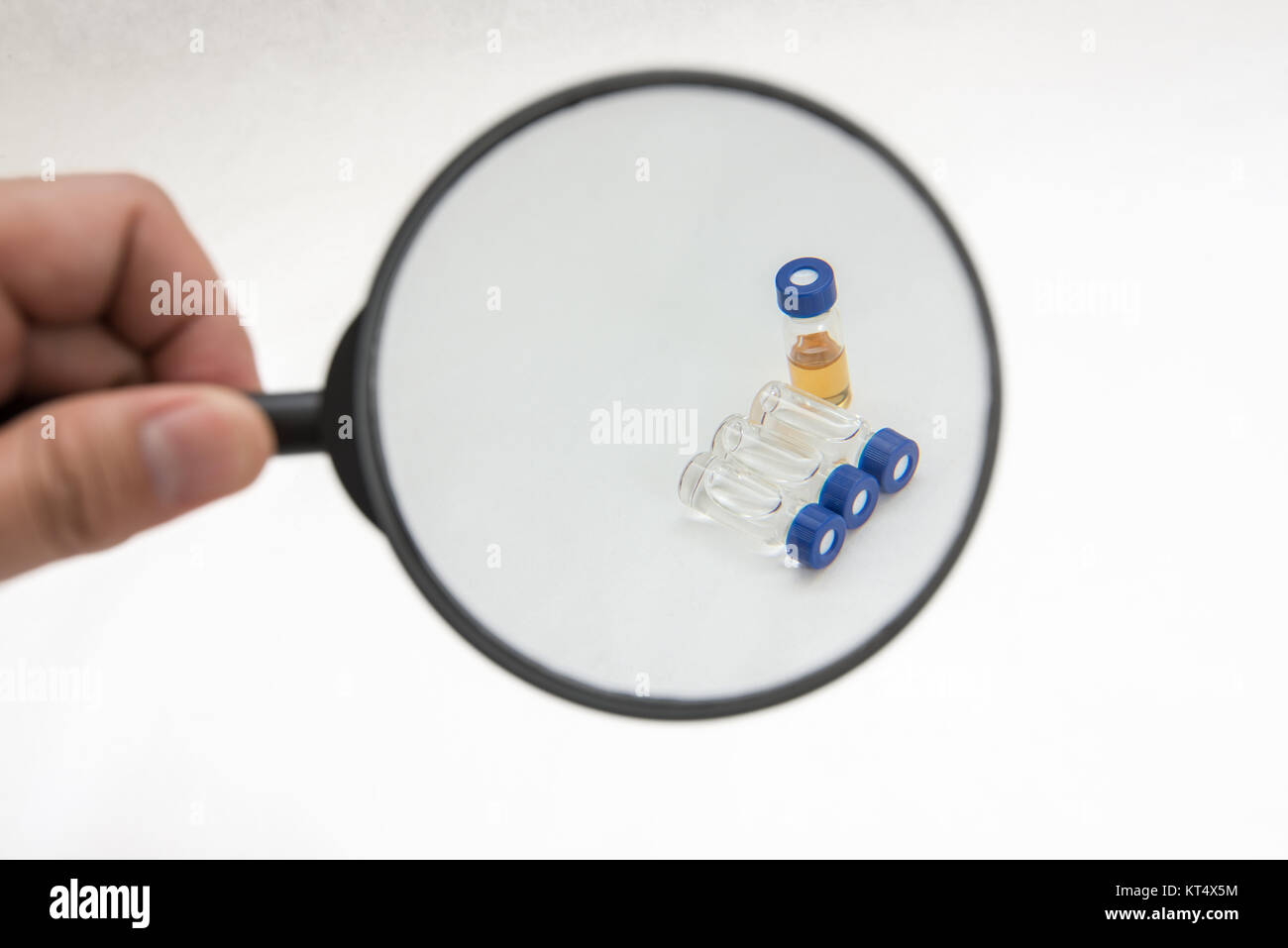 Handing magnify glass on sample vial Stock Photo - Alamy
