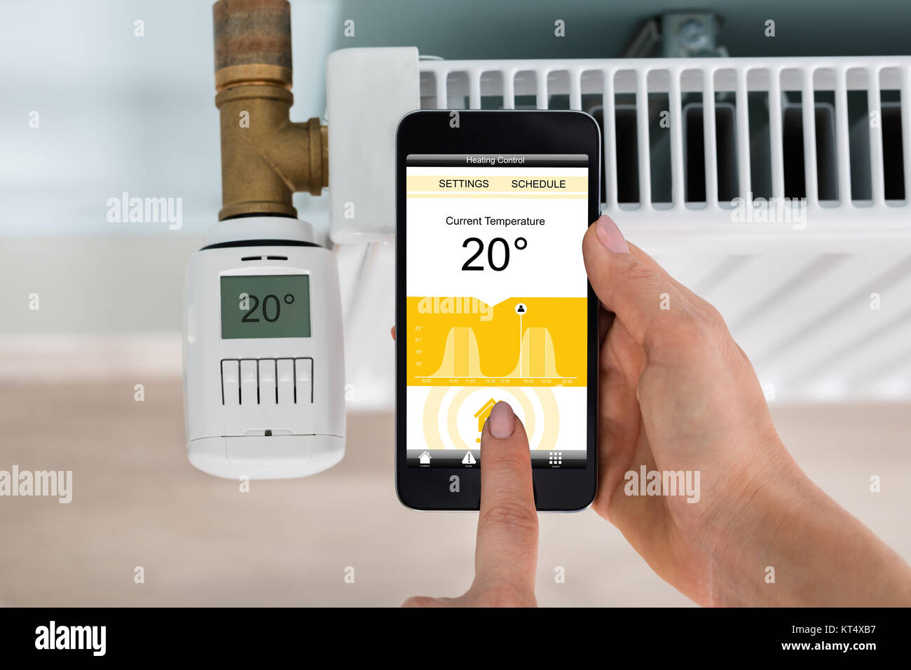 Person Setting Temperature Of Thermostat Using Mobilephone Stock Photo ...
