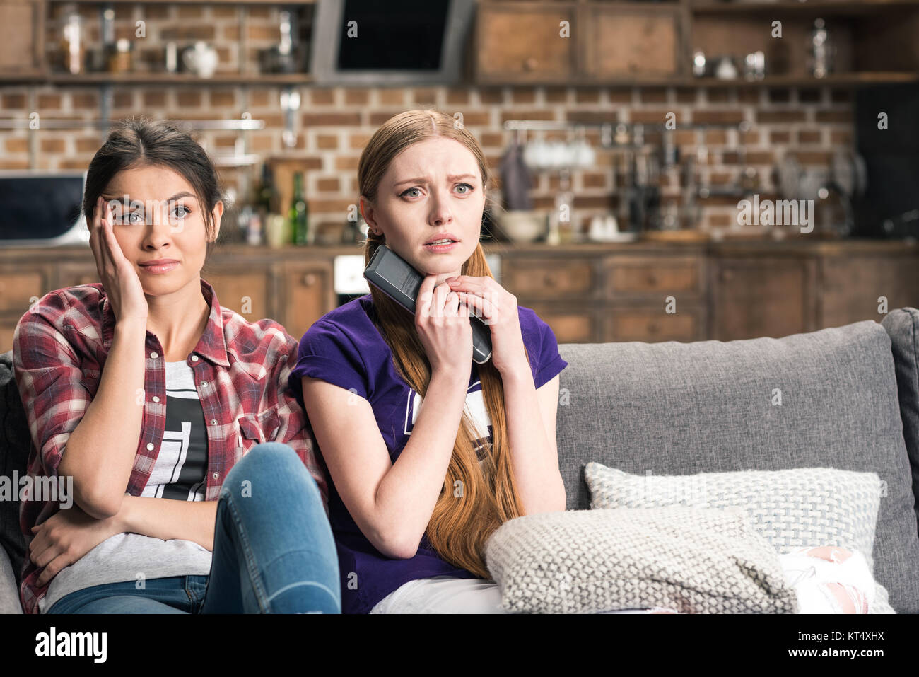 Young scared women sitting on sofa and watching tv Stock Photo - Alamy