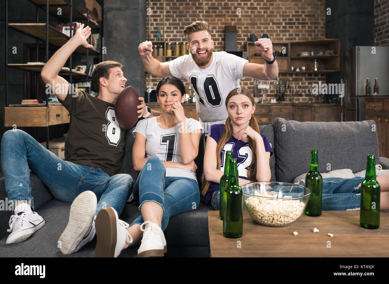 Bored young women sitting near excited men supporting favorite football ...