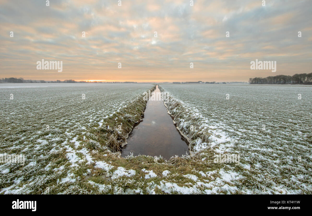 Frozen grassland with straight river canal in center dissapearing on ...