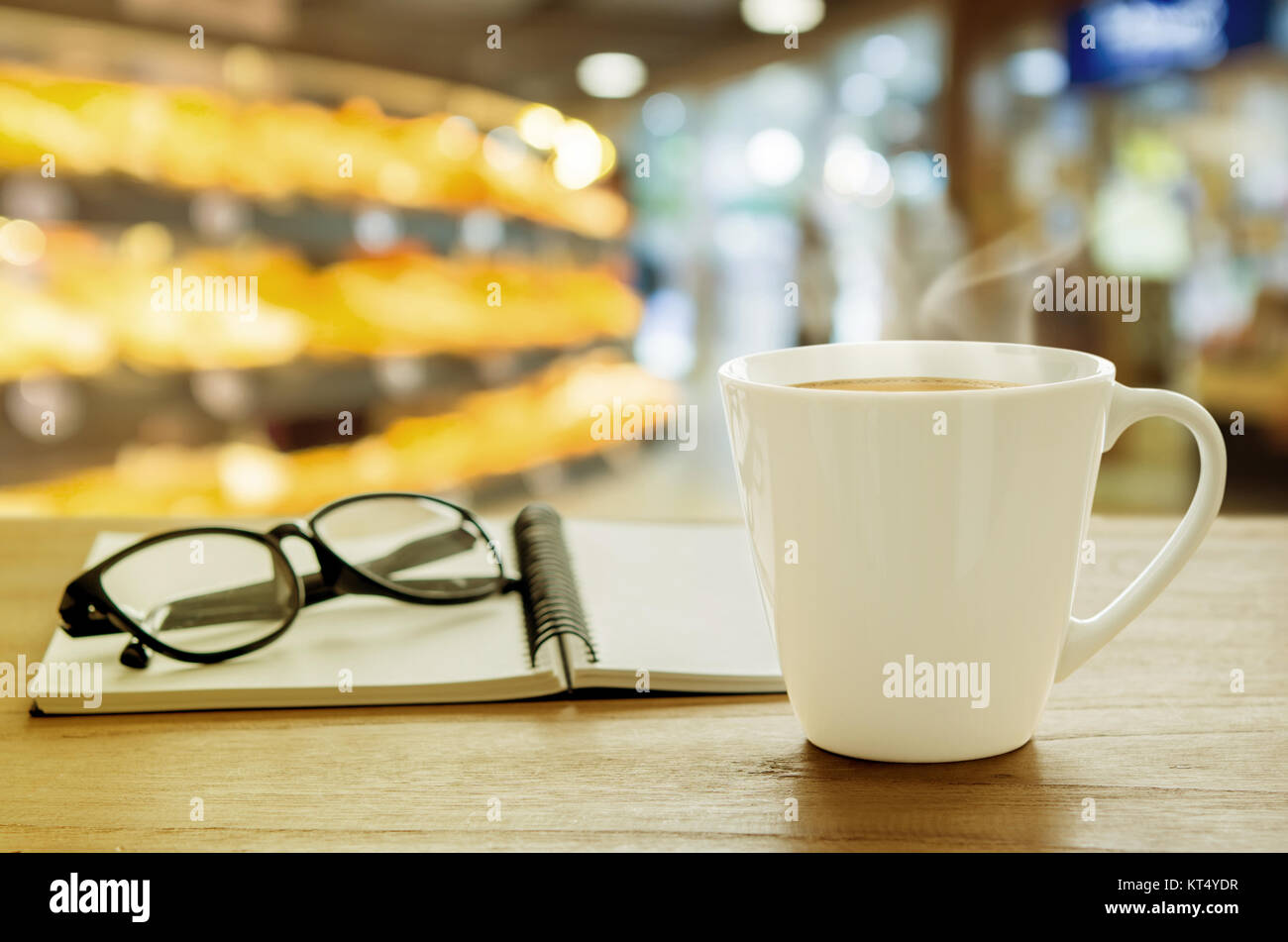 Cup of coffee and note book on wooden table. Coffee break in morning ...